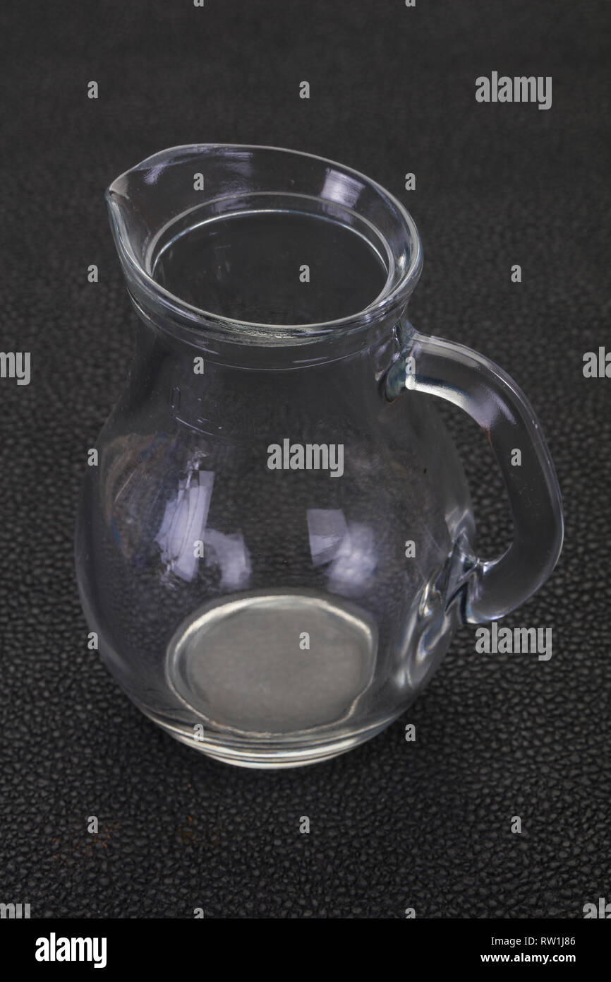Empty glass jug over black background Stock Photo - Alamy