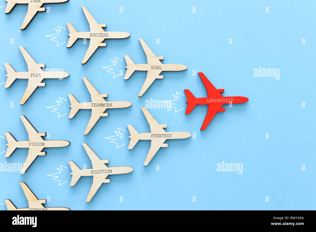 Leadership concept with airplanes on blue wooden background. One red ...