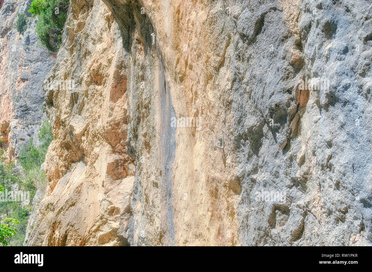 Climbing wall at the hillside of a rocky mountain. Carabiners ready to ...