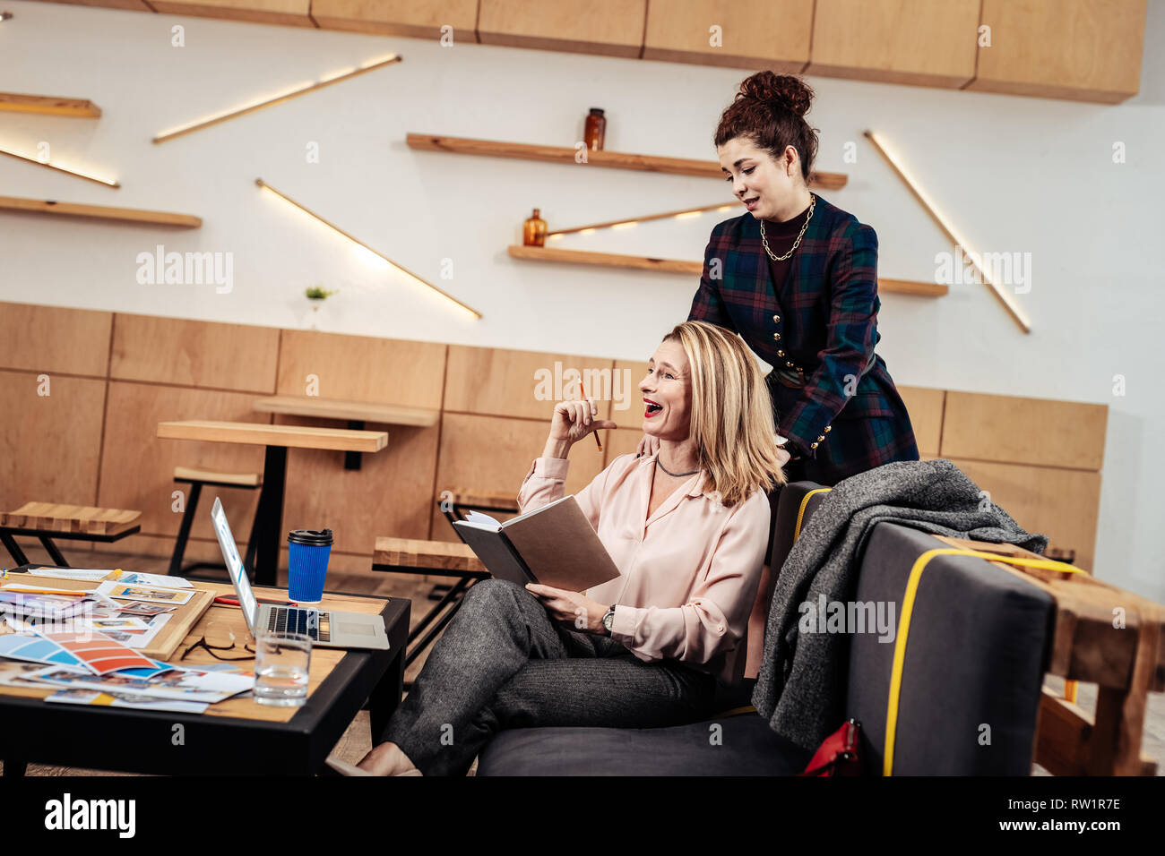 Female boss laughing while having massage by assistant Stock Photo - Alamy