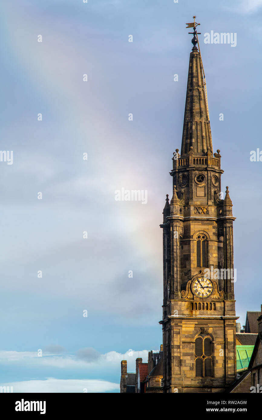 A rainbow appears in the sky behind spire of gothic church, Edinburgh ...