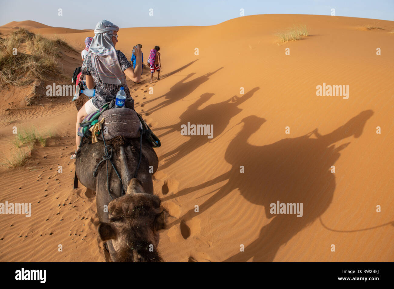 The shadows of camelback riders stretched out across the sand dunes ...