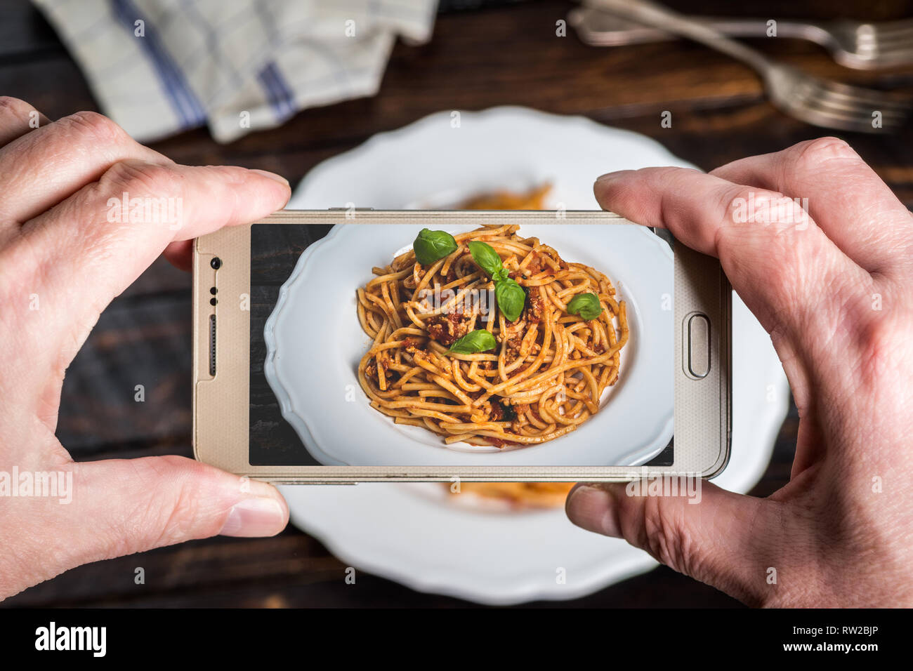 Man taking photo on mobile phone of pasta spaghetti bolognese ...