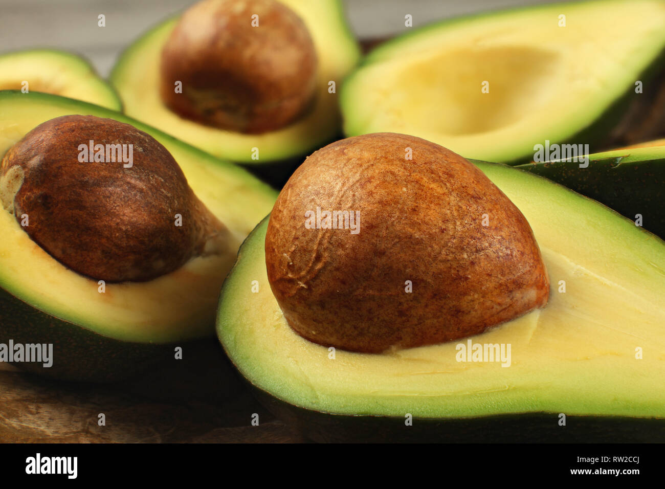 Avocado fruits cut in half, seed visible, close up photo, showing ...