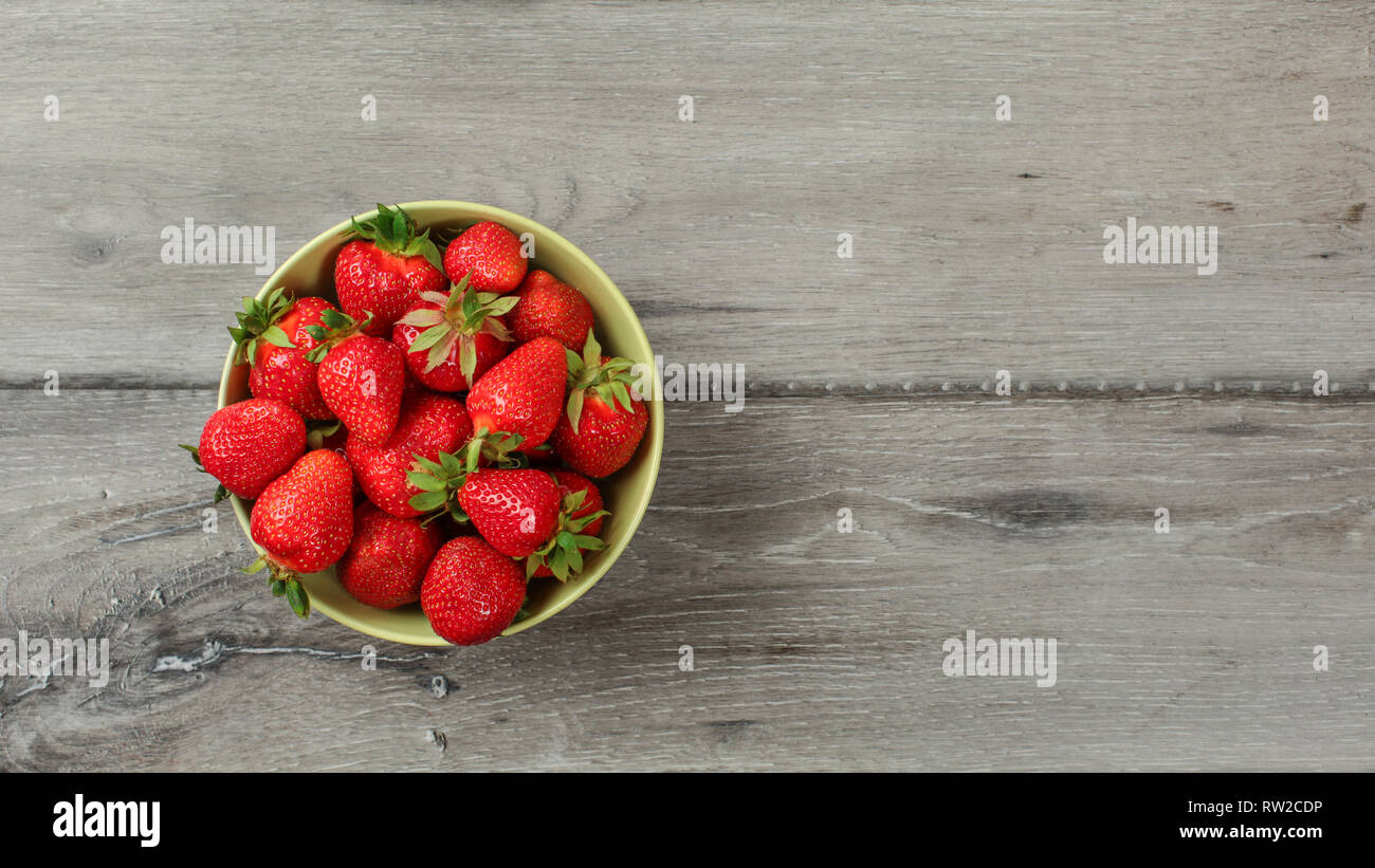 Top down view, small bowl with strawberries on gray wood desk. Space ...