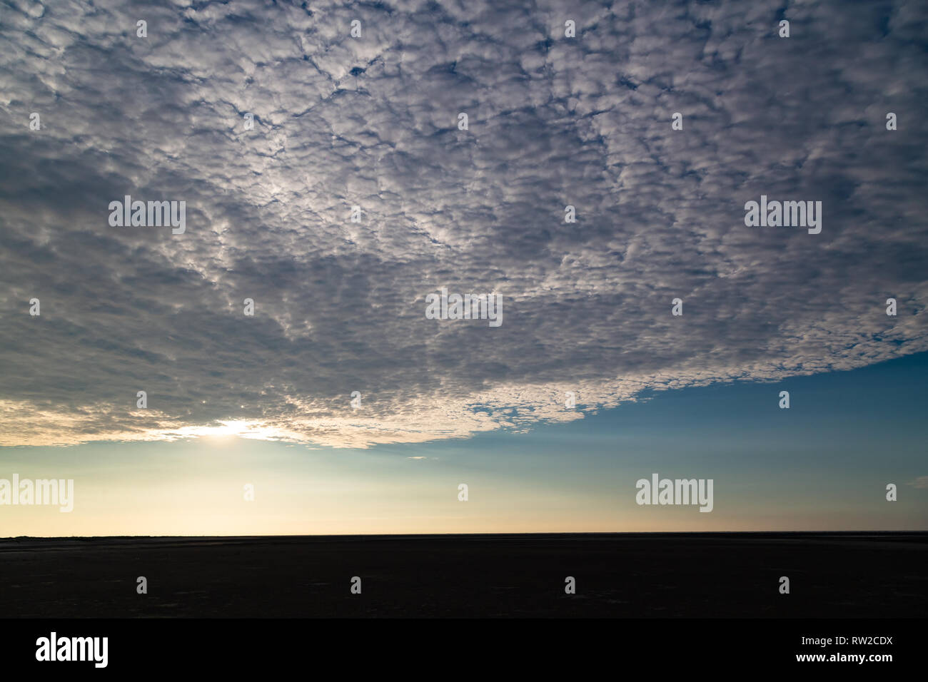 Strange sunset with bright clouds over the sun and the sea with a ...