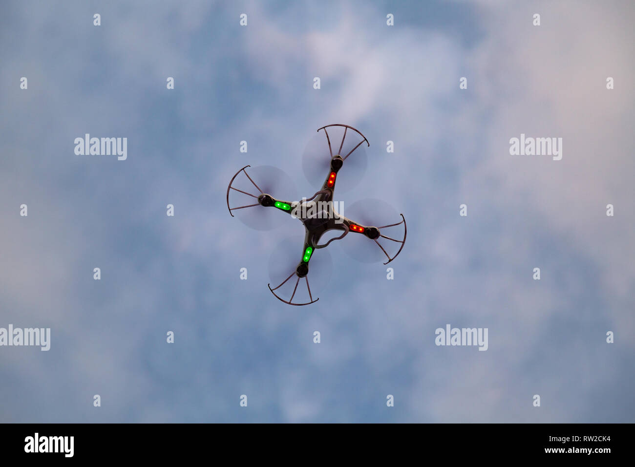 Small generic drone with its lights, flying with a light blue ...