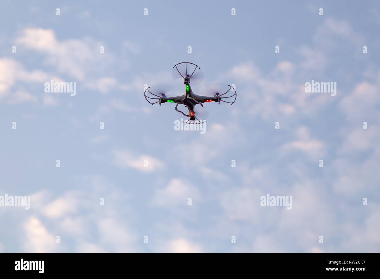 Small generic drone with its lights, flying with a light blue ...