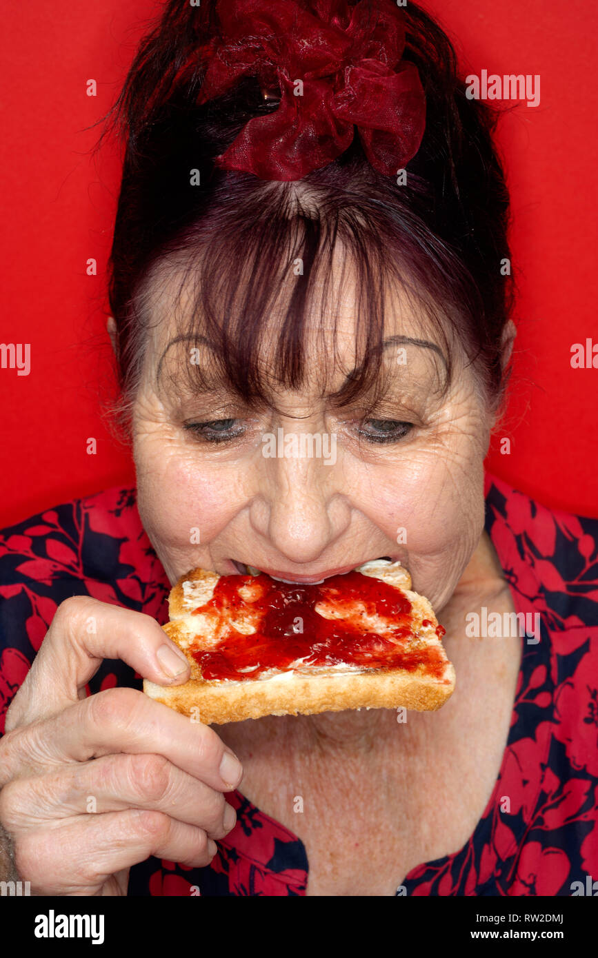 Elderly woman eating strawberry jam on toast Stock Photo - Alamy