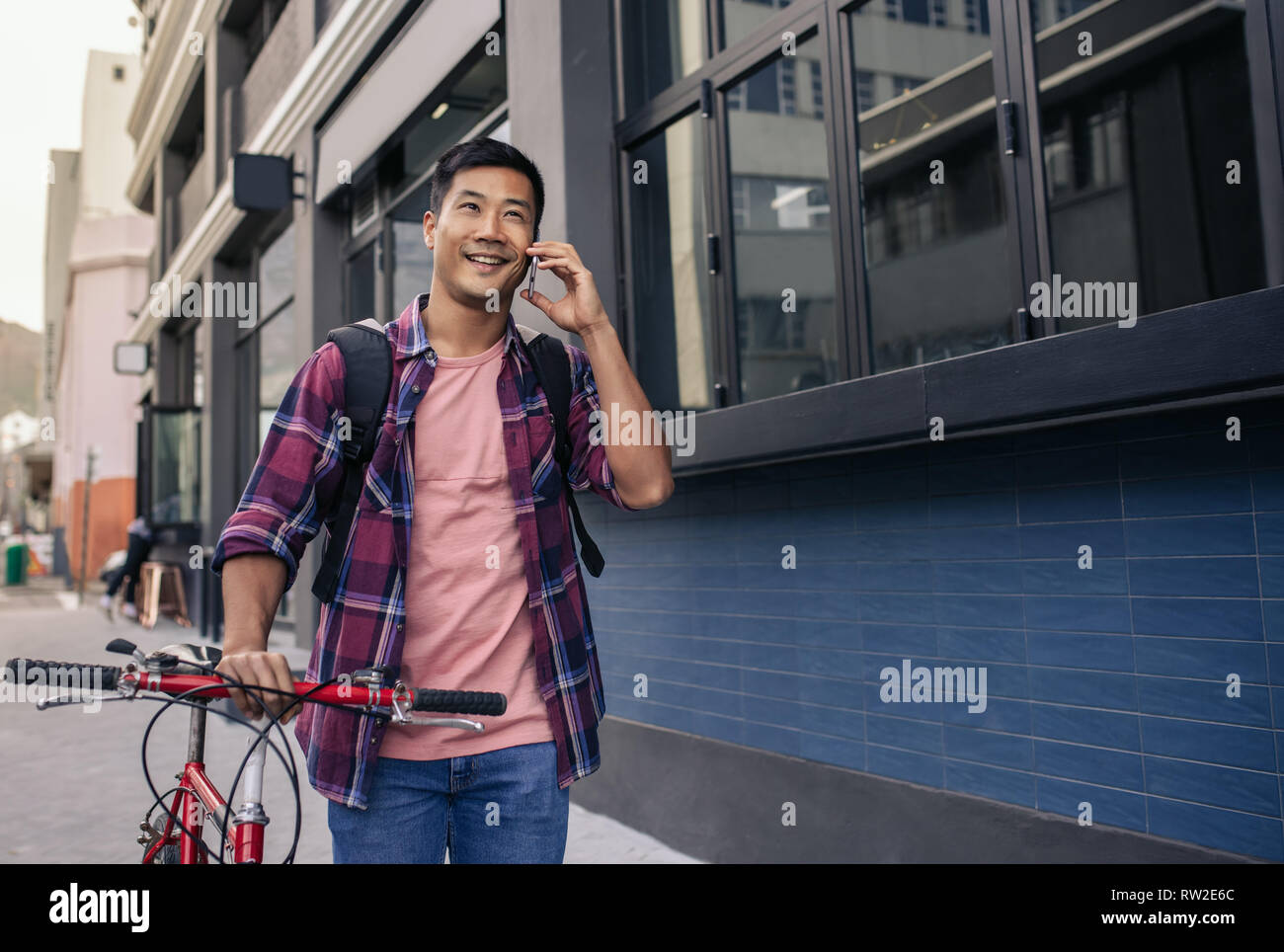 Smiling man walking with his bike talking on a cellphone Stock Photo ...