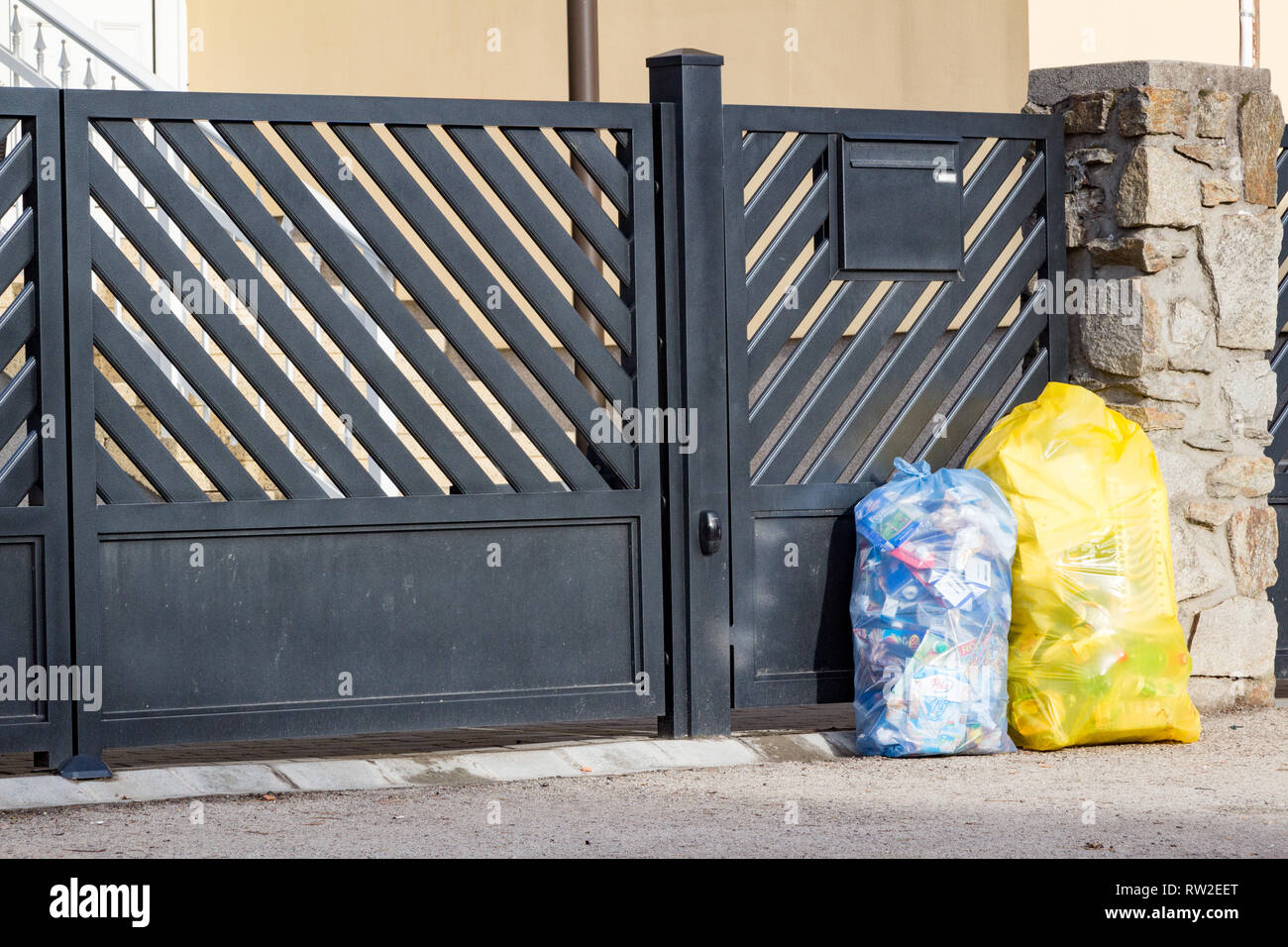 House gate and bags of separate collection of plastic and carton waste ...