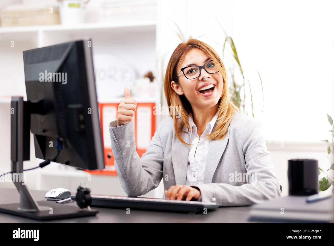 businesswoman thumbs up infront of a computer in an office Stock Photo ...