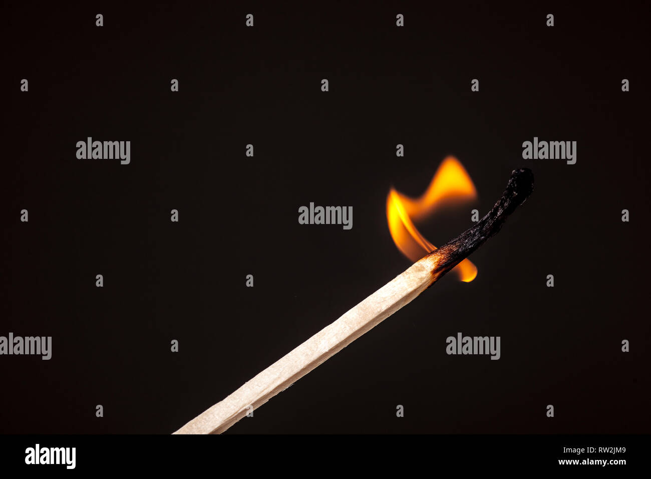 one long match stick burning against black background Stock Photo - Alamy