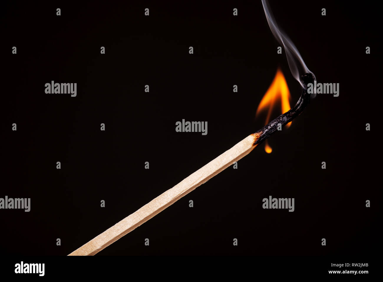 one long match stick burning against black background Stock Photo - Alamy