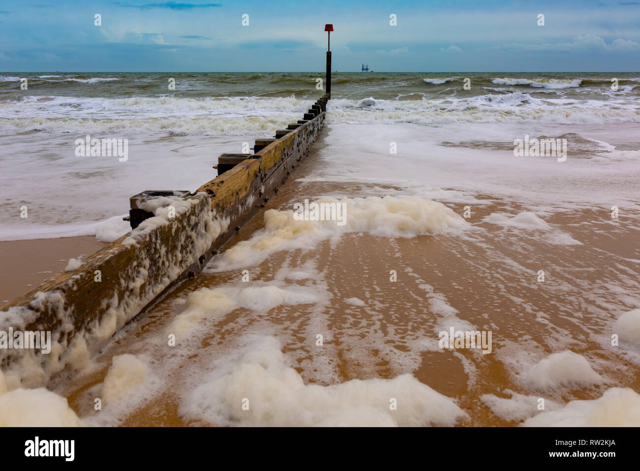 Landscape photograph of rough sea depositing large amounts of froth on ...