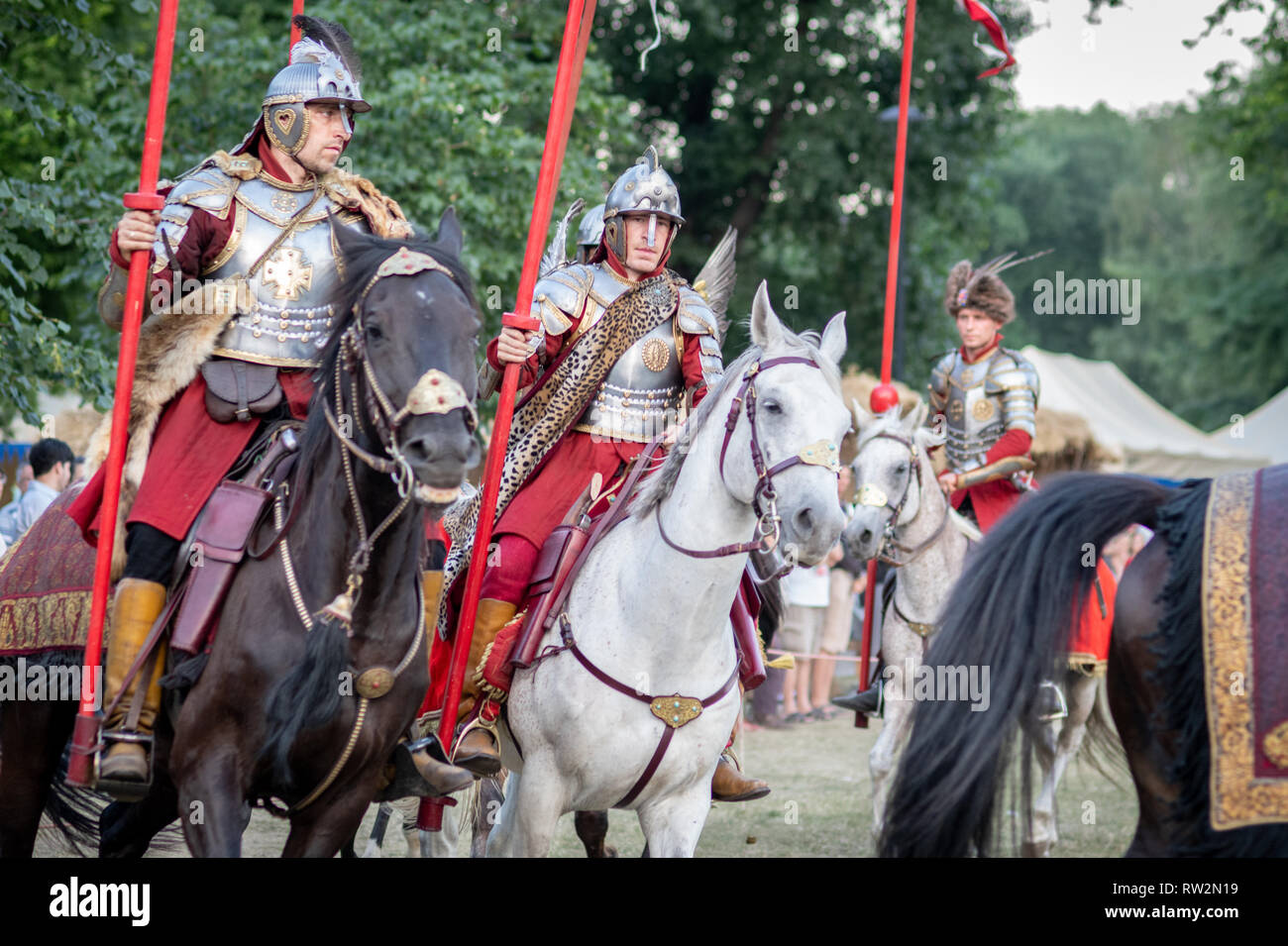Men dressed in medieval costumes and armour carry lances in their hands ...