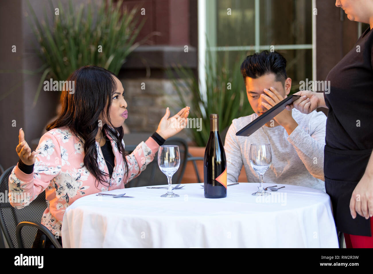 Couple on a date angry at a waitress in an outdoor restaurant. They are ...