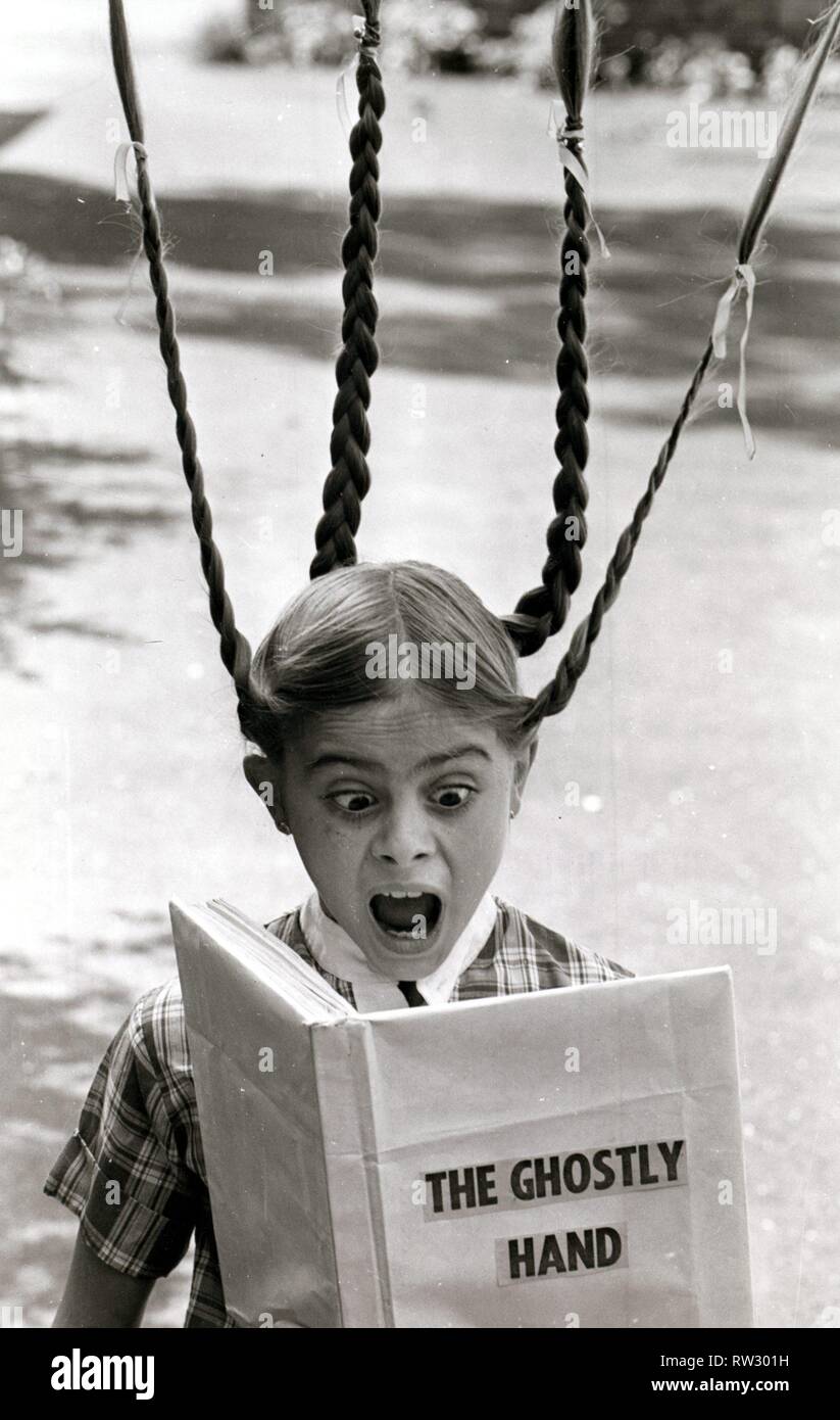 A girl's pigtails stand on end in terror as she reads a scary ghost ...