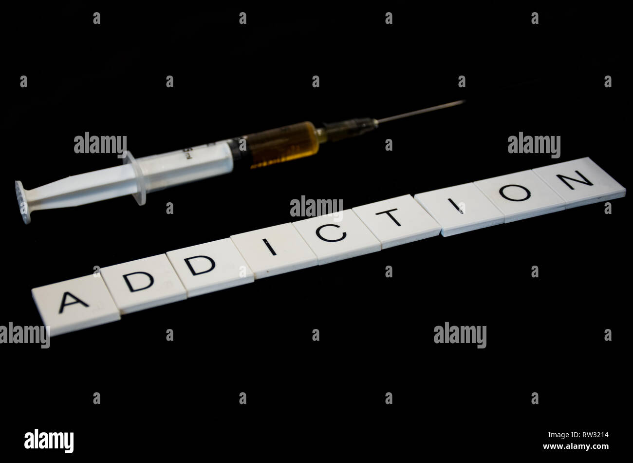 Word addiction in uppercase letters with syringe full of drug on black ...