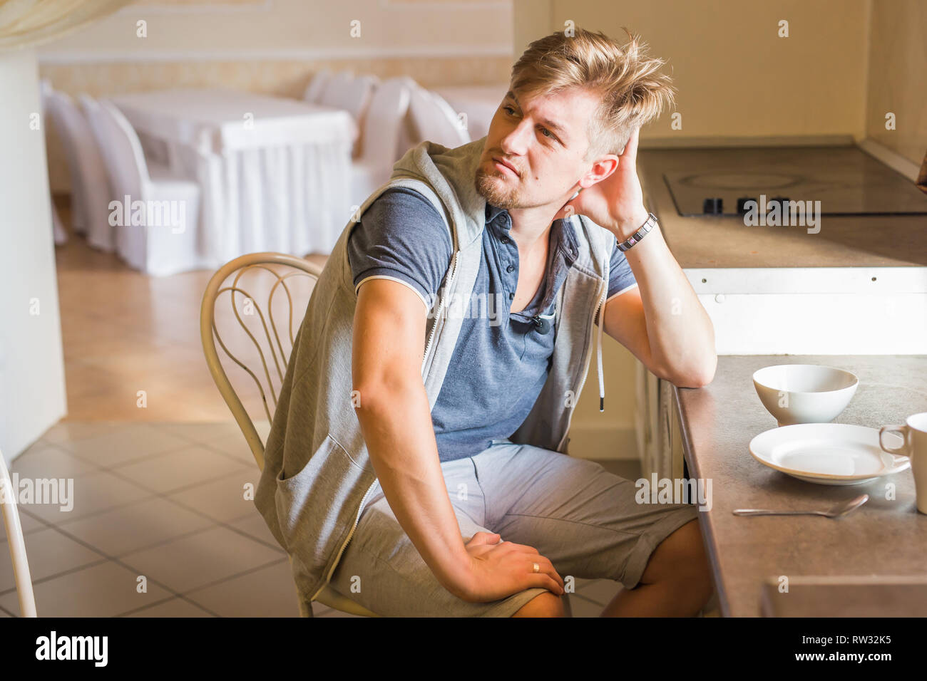 young cute sad man sitting at a table with a plate leaning on his arm ...