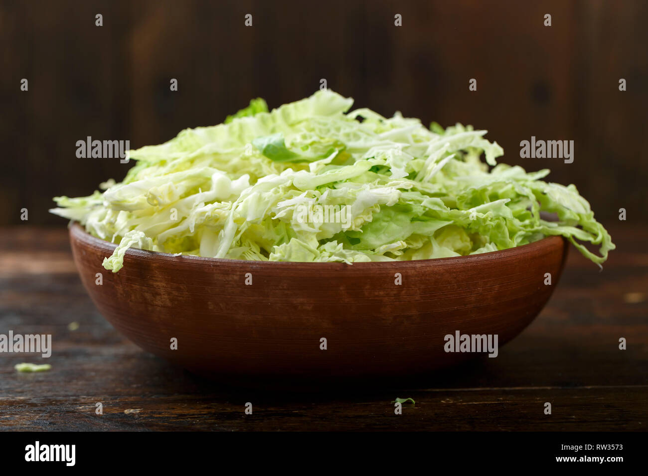 finely chopped savoy cabbage in a plate on a wooden background. space ...
