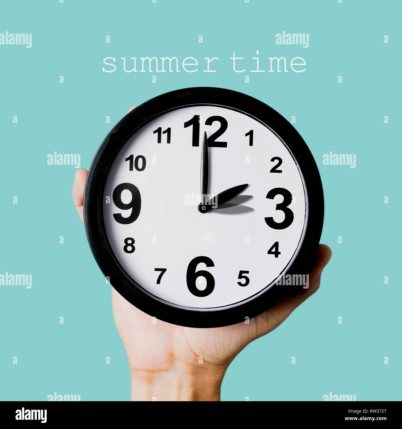 closeup of the hand of a young caucasian man holding a clock, which is ...