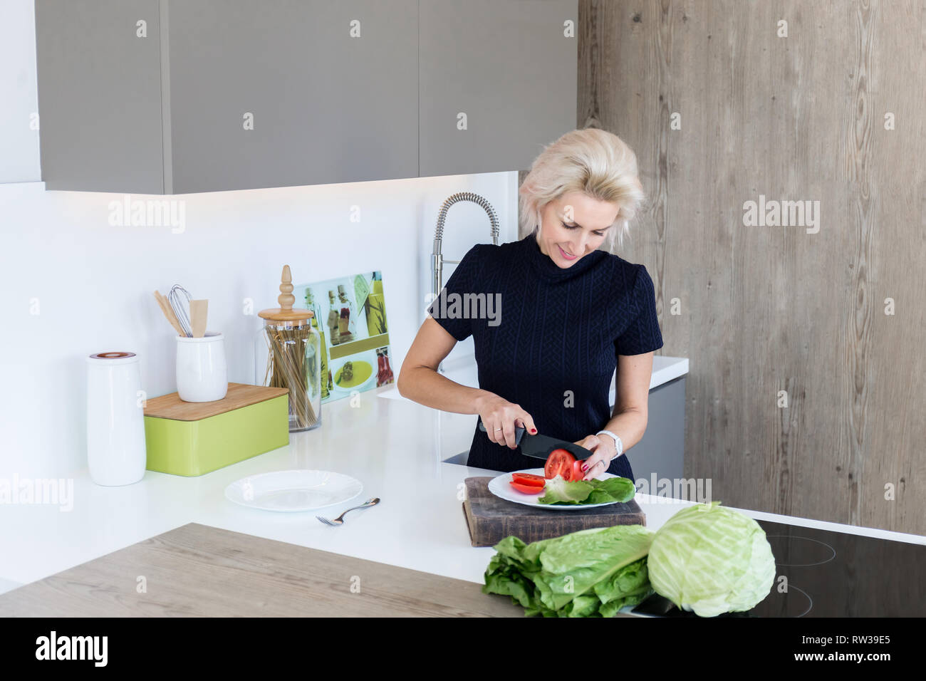 young blonde woman cooking in modern kitchen Stock Photo - Alamy
