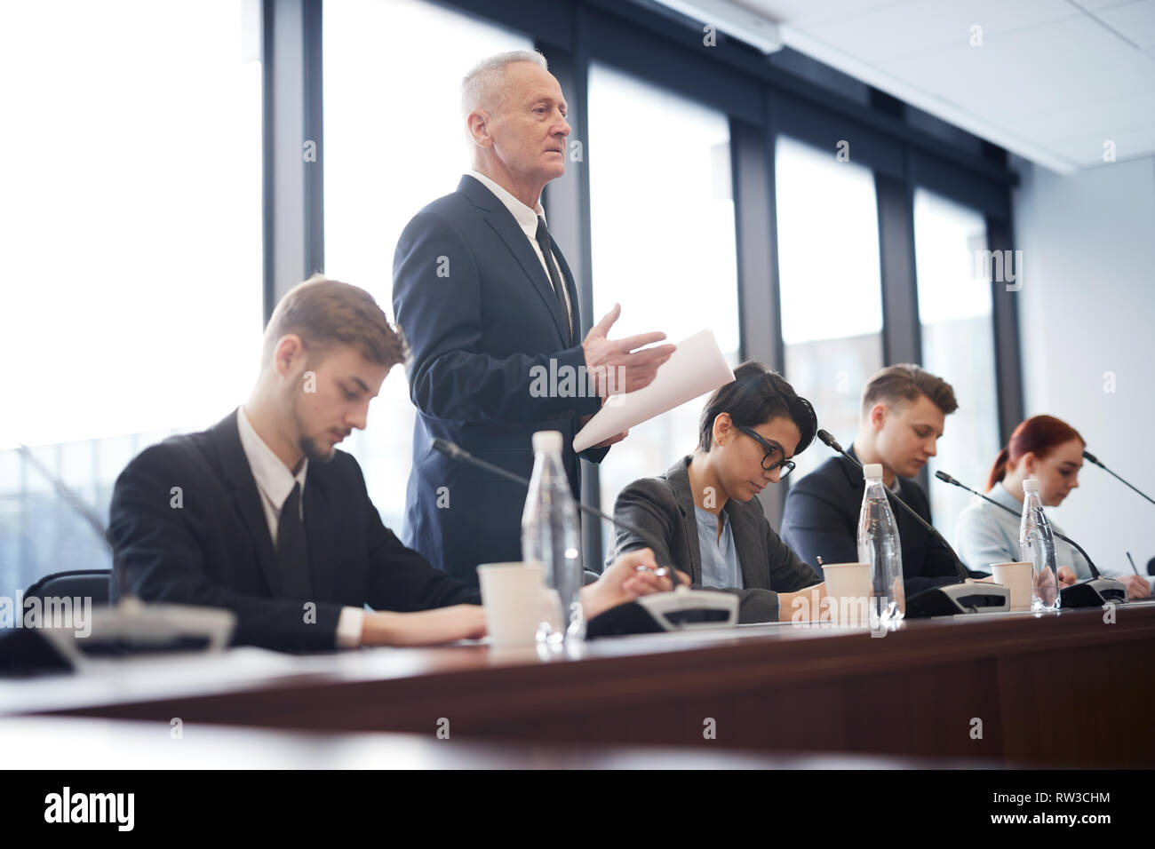 Side view portrait of senior businessman talking to colleagues at ...