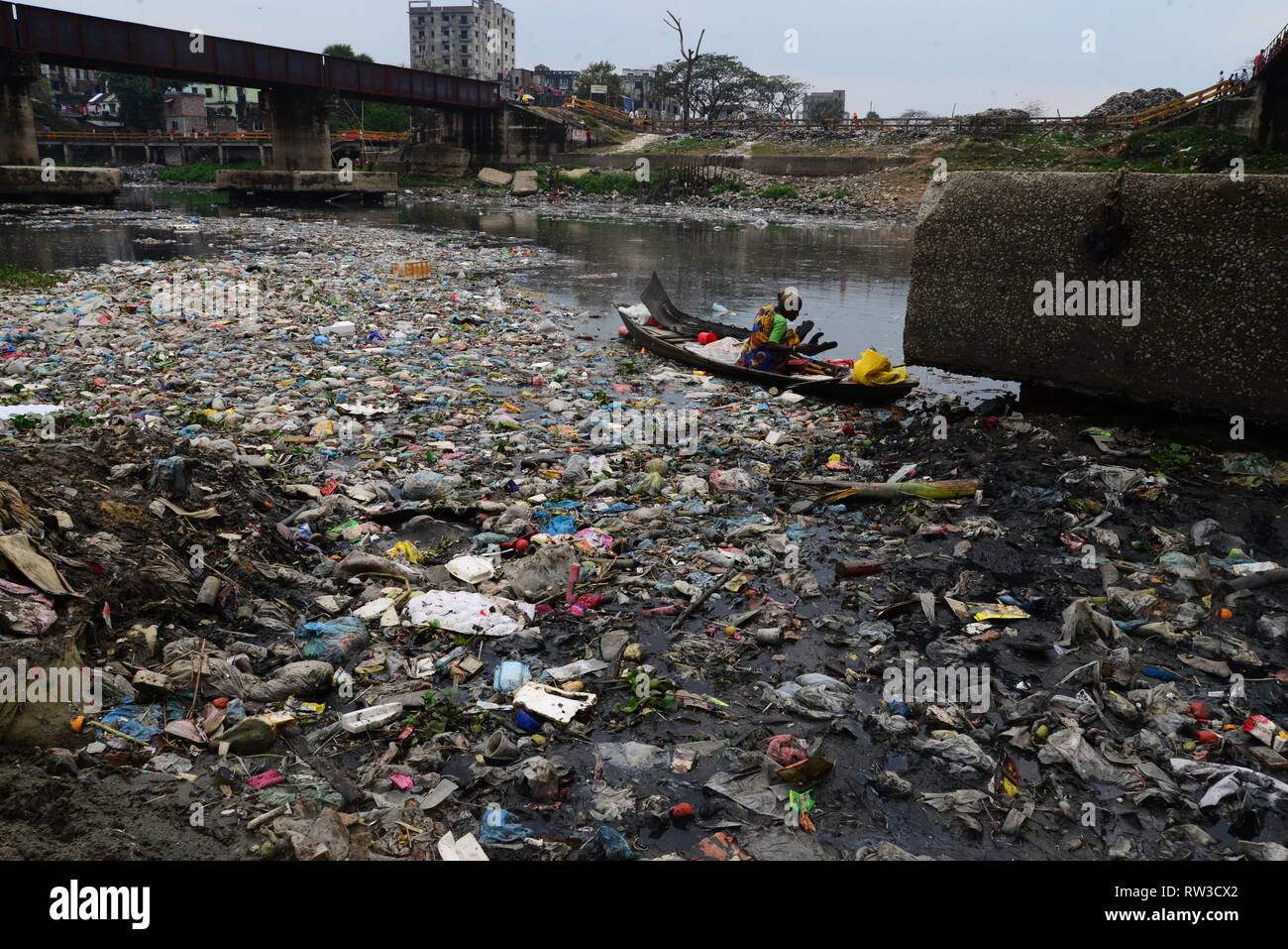 A Bangladesh woman collects plastic from the polluted Turag River in ...