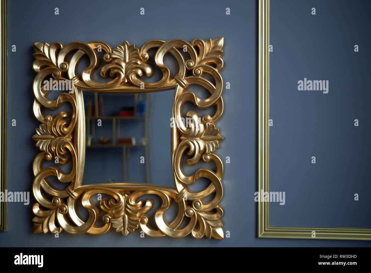 Mirror in a gold tracery frame on the background of the classic gray ...