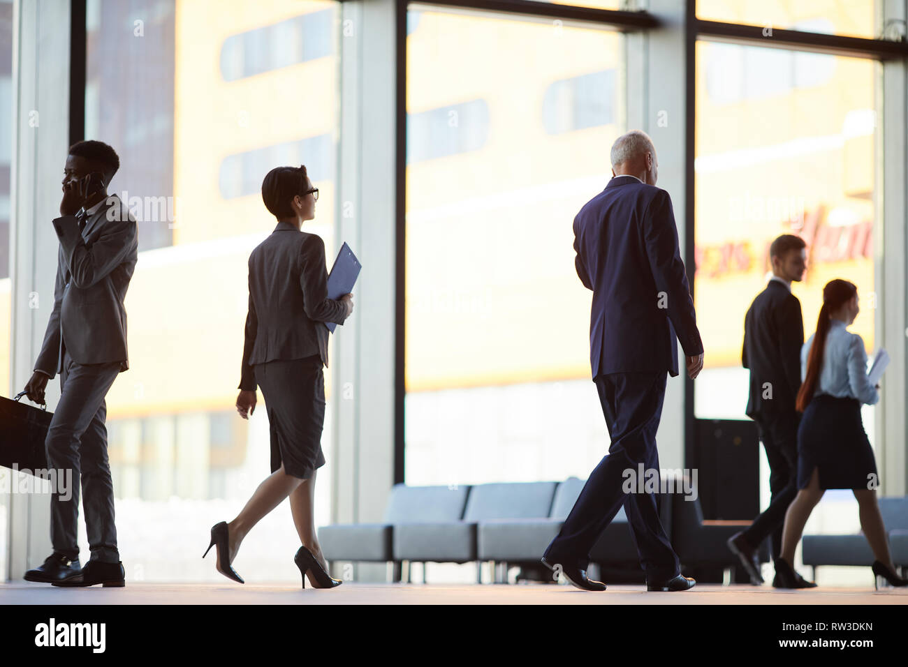 Back view of business people walking in office hall or lobby, copy ...