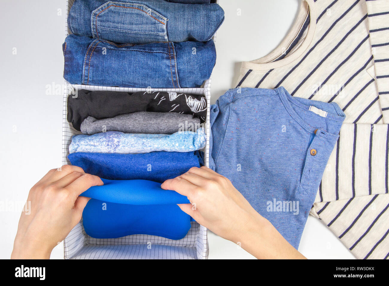 Woman hands tidying up kids clothes in basket. Vertical storage of ...