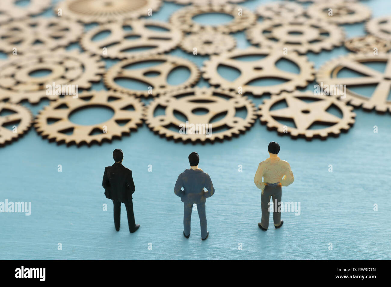 Miniature people looking at cogwheel in set of gears mechanism. Problem ...