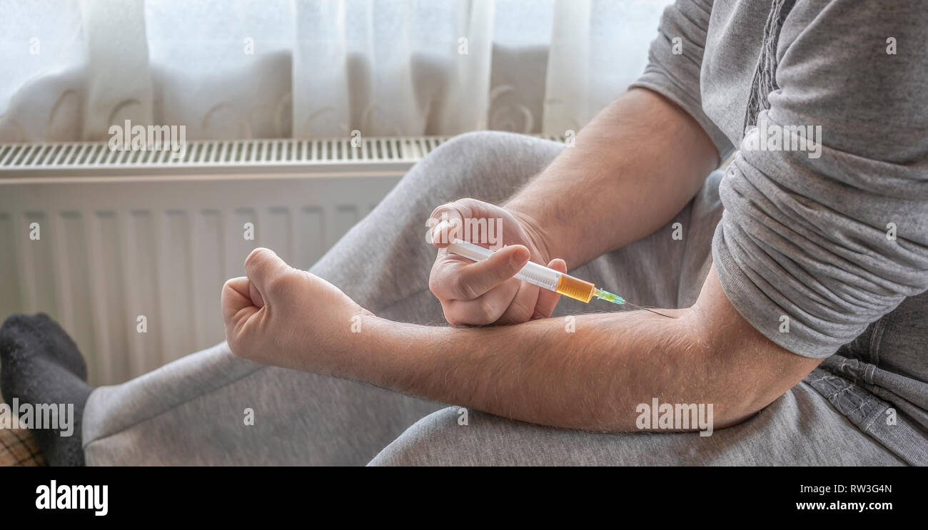 A drug addict who runs a needle in the vein and injects a dose of ...