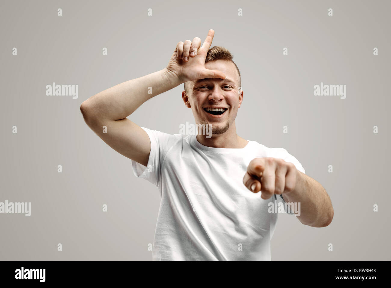 Losers go home. Portrait of happy guy showing loser sign over forehead ...