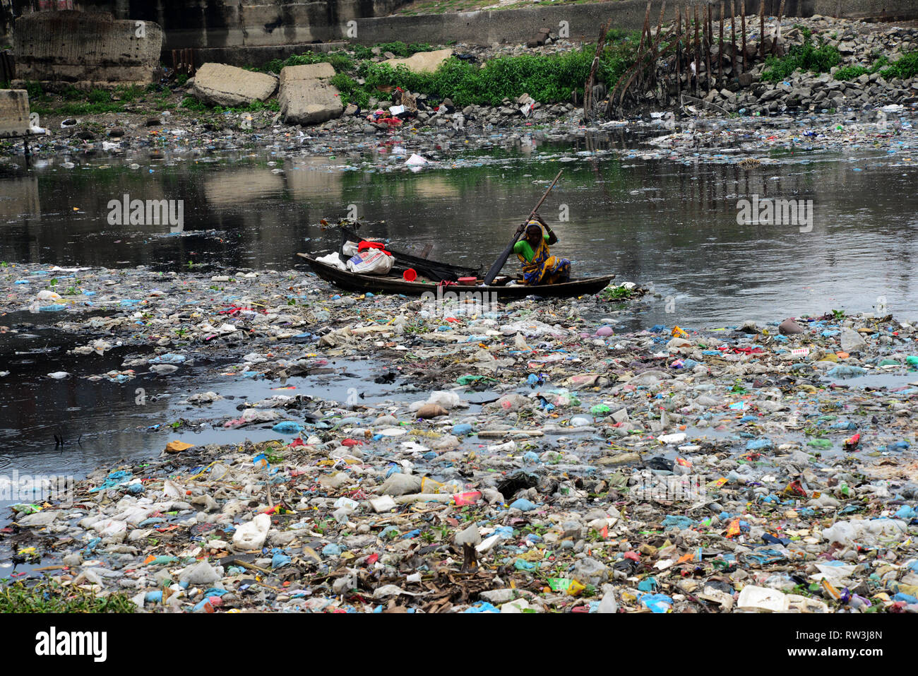 A Bangladesh woman collects plastic from the polluted Turag River in ...