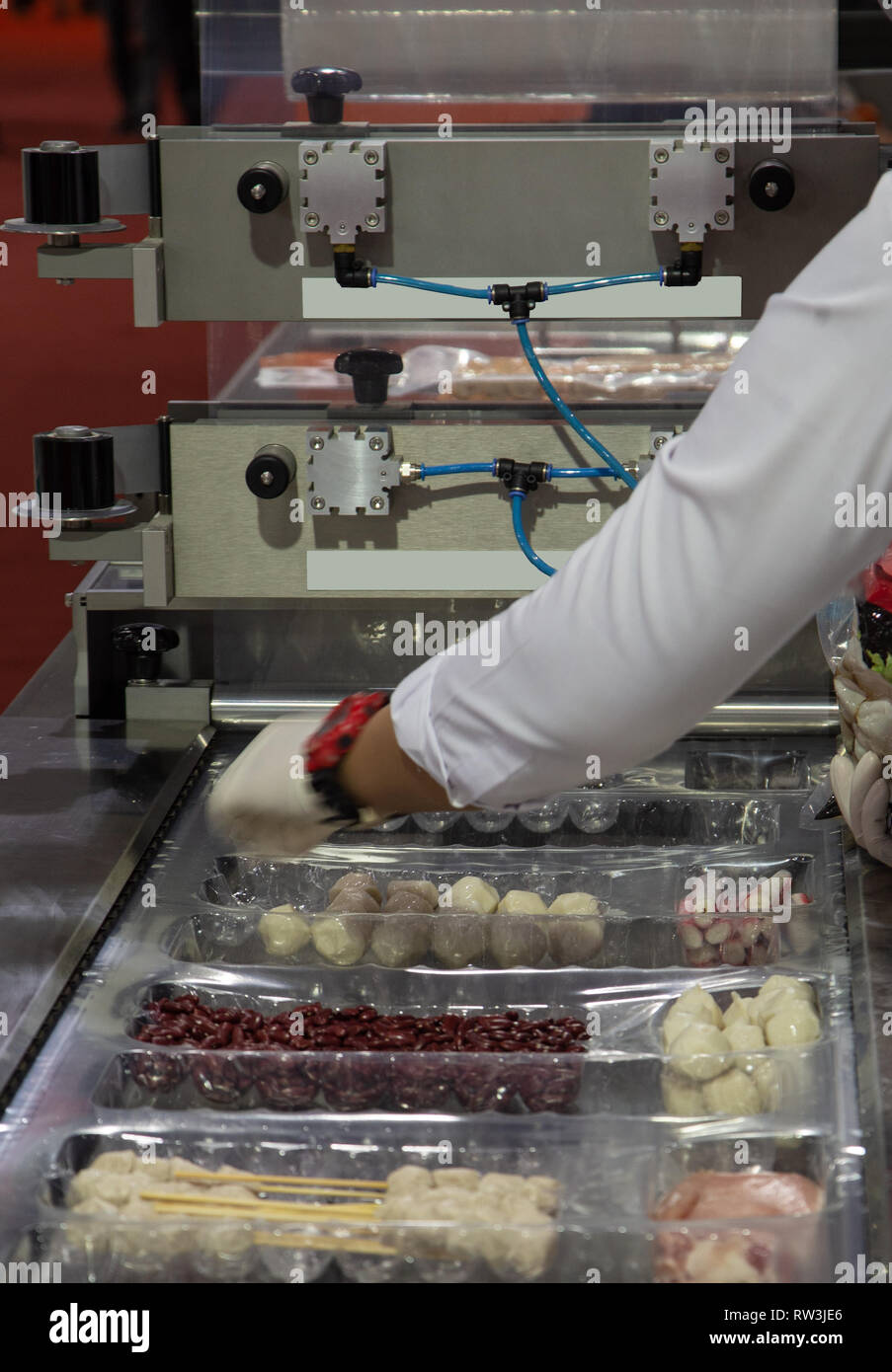 Worker put food in plastic tray for packing food in machine Stock Photo ...