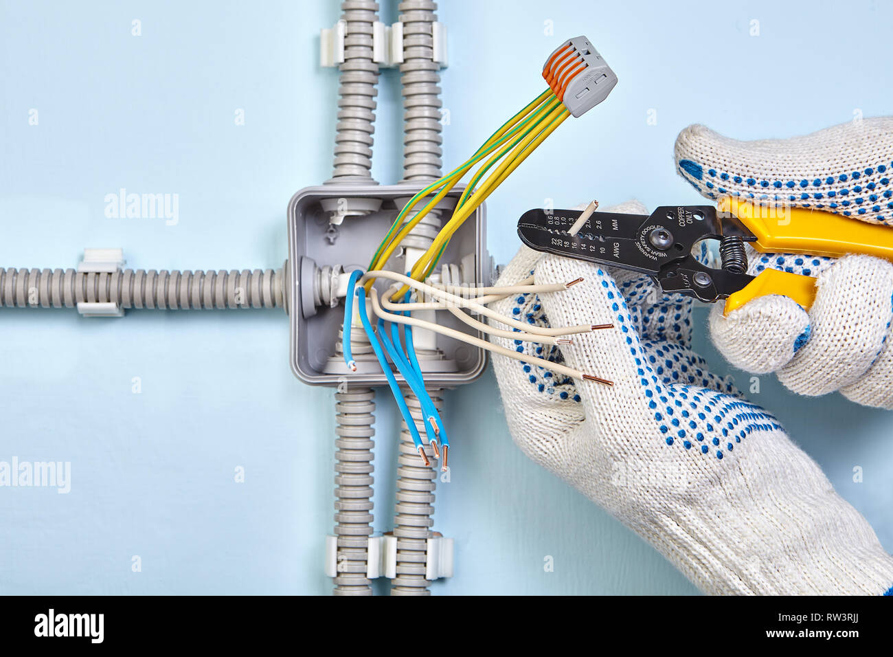 An electrician is stripping of wire insulation using a wire stripper ...