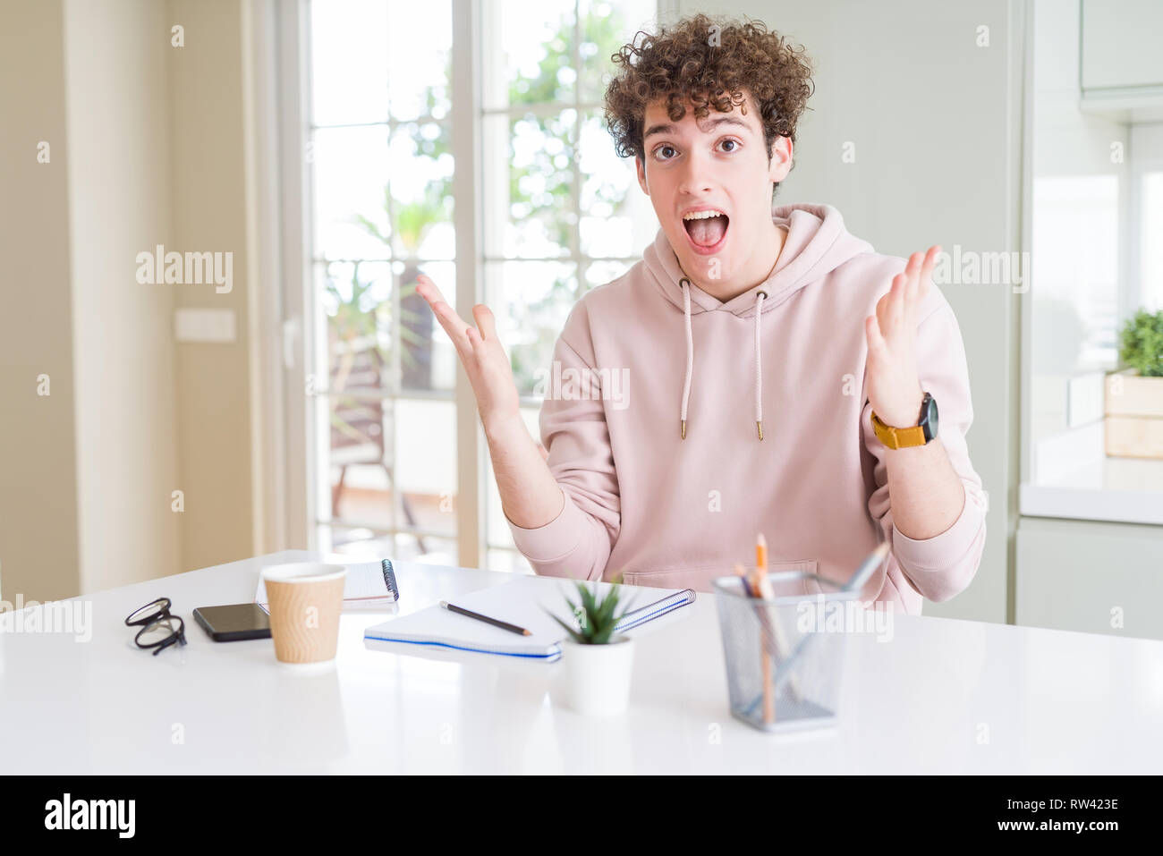 Young student man writing on notebook and studying celebrating crazy ...