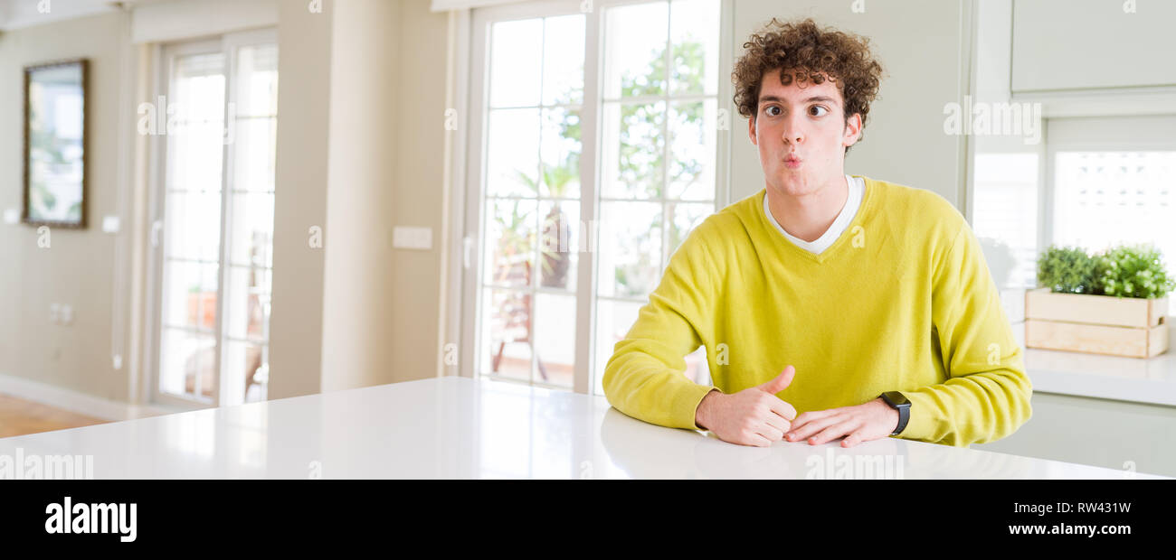Wide angle shot of young handsome man at home making fish face with ...