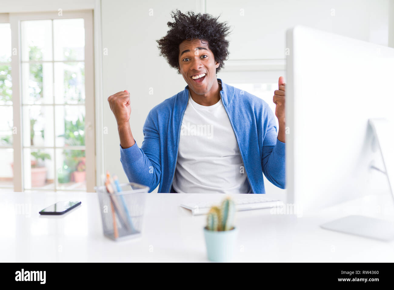 African American man working using computer screaming proud and ...