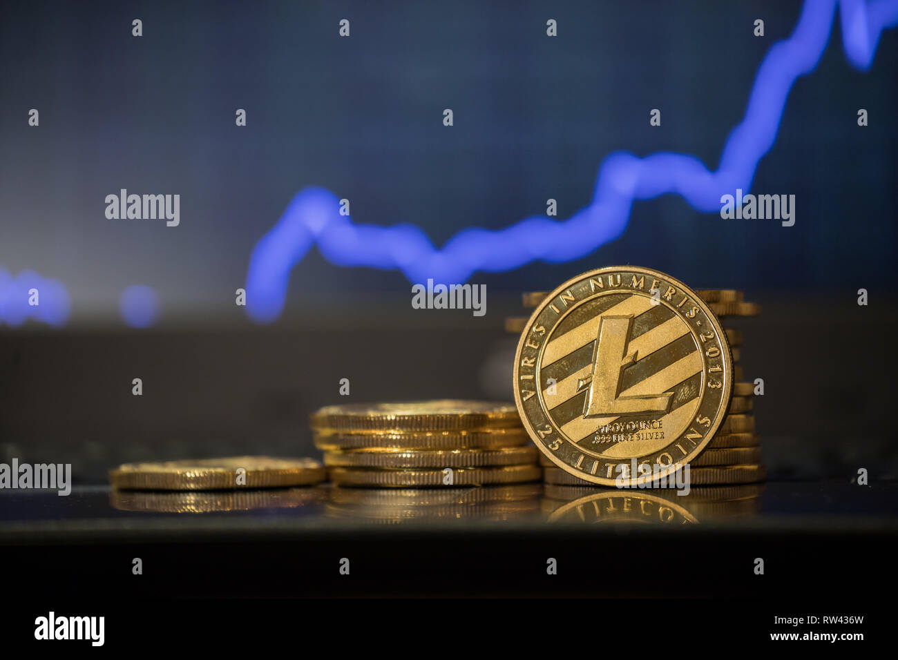 Golden Lightcoin on defocused blue chart background Stock Photo - Alamy