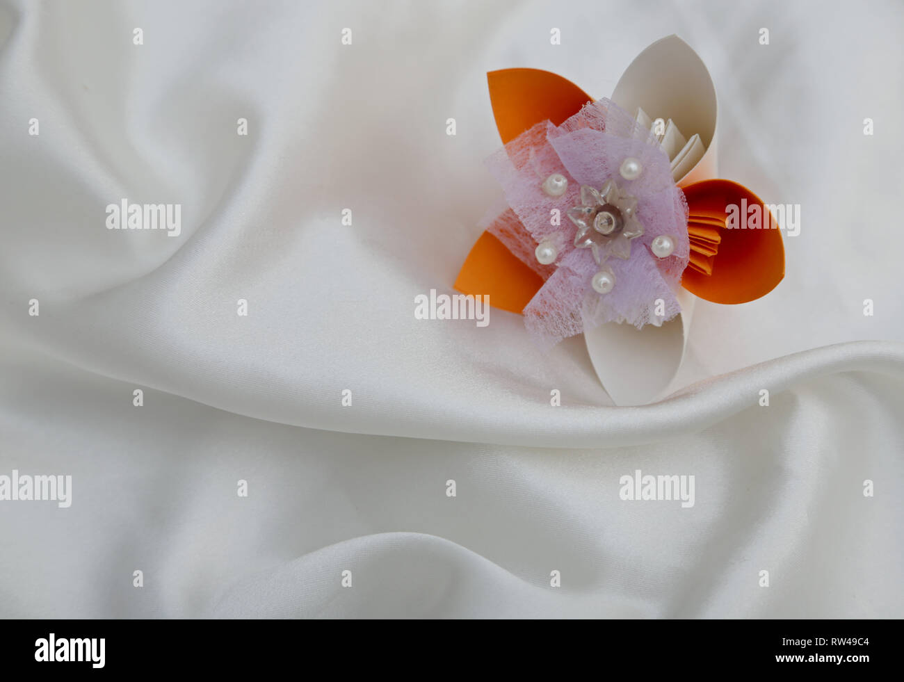 Beautiful colourful folded origami flower on a white shiny textile ...