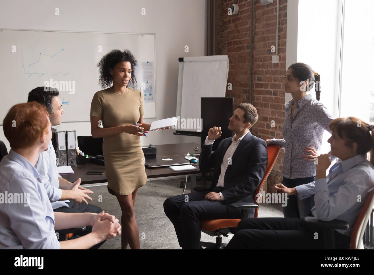 Serious female african coach mentor speaking at diverse team meeting ...