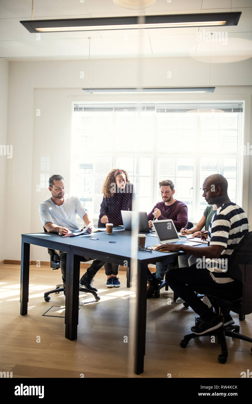 Diverse group of focused young designers discussing work together while ...