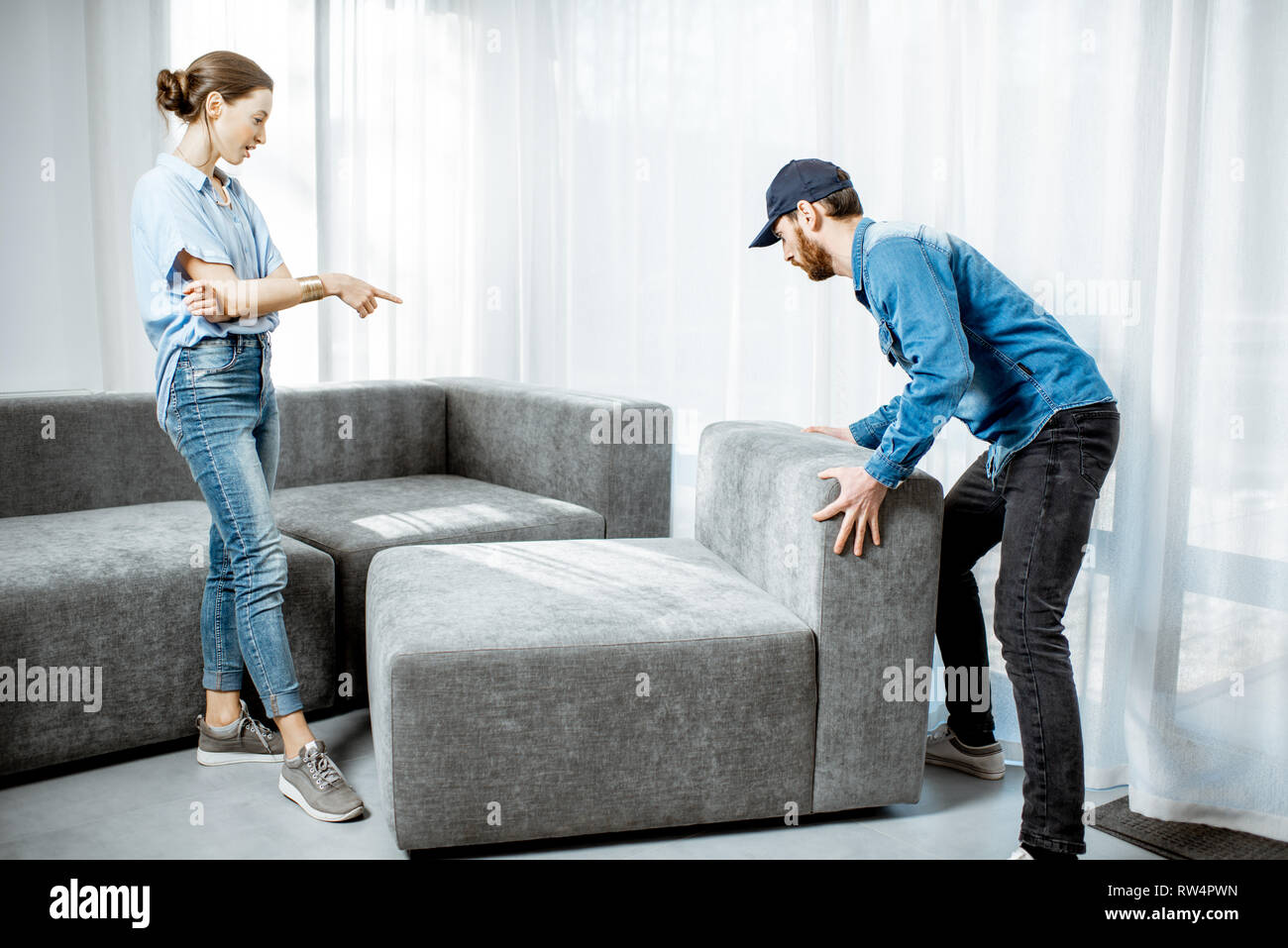 Delivery man mounting new sofa for a young woman client in the modern ...
