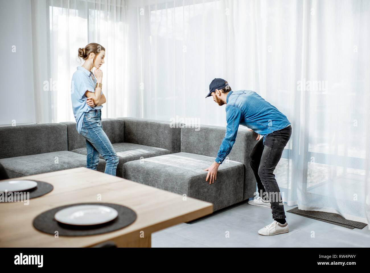 Delivery man mounting new sofa for a young woman client in the modern ...