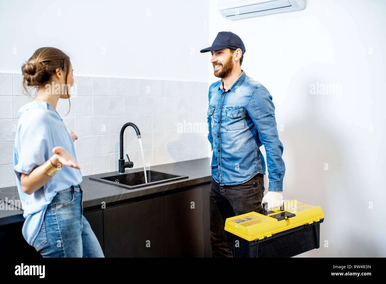 Handy man talking with young woman client after the repairment on the ...
