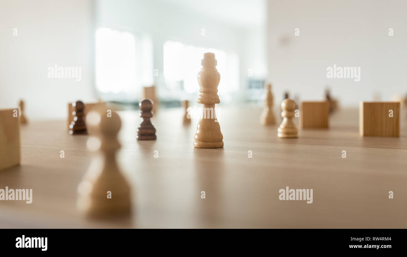 Chess figure king in the middle of an office desk wit other figures ...