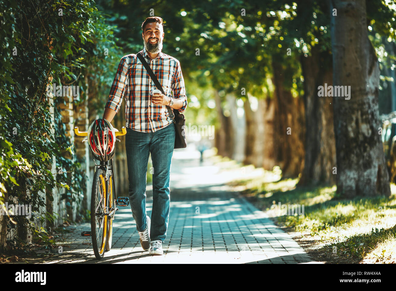 A handsome young man goes to the city ride with his bike, walking with ...